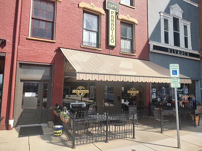 The vibrant red brick facade of Cafe Paradiso stands proudly on Monument Square, its awning and outdoor seating beckoning like an old friend with good news to share.