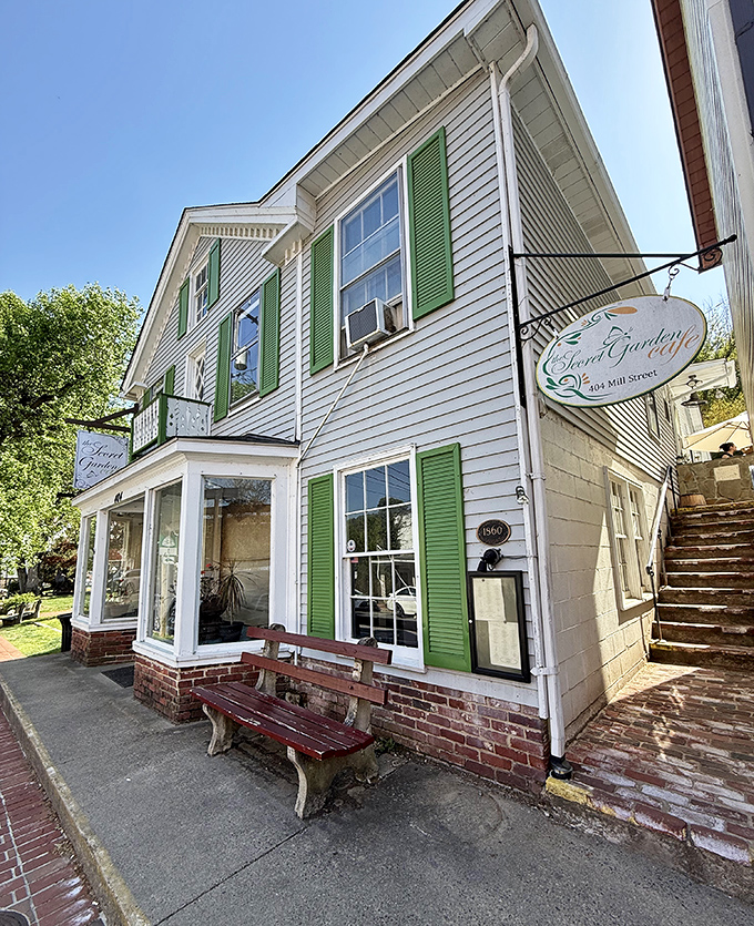 Perched on Mill Street like a culinary lighthouse, the cafe's hanging sign promises garden delights while the weathered bench offers a moment to savor the anticipation.