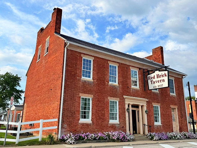 The historic Red Brick Tavern stands proudly against an Ohio sky, its weathered facade whispering tales of presidential visits and centuries of hungry travelers.