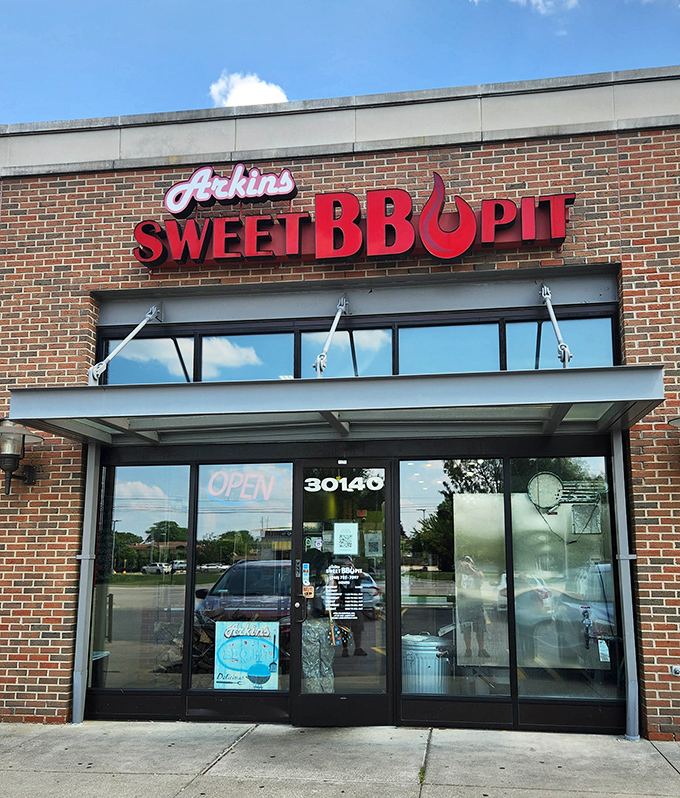 The brick facade and bold red signage of Arkins Sweet BBQ Pit promises smoky treasures within, like a barbecue beacon calling to hungry travelers.