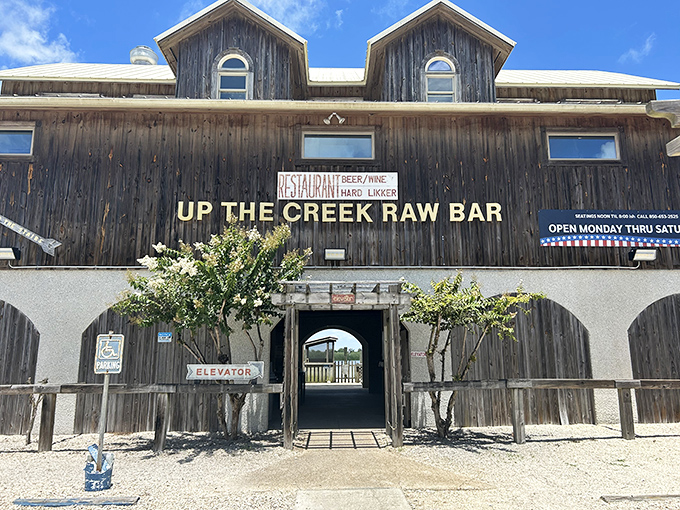 The weathered wooden exterior of Up The Creek Raw Bar stands like a salty sea captain against Florida's brilliant blue sky, promising authentic maritime delights within.