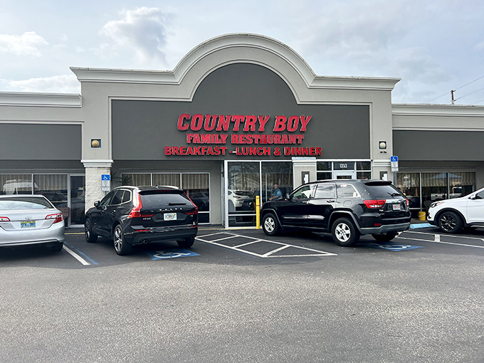 The bright red signage of Country Boy Restaurant stands out like a beacon for hungry travelers, promising homestyle meals without pretension.