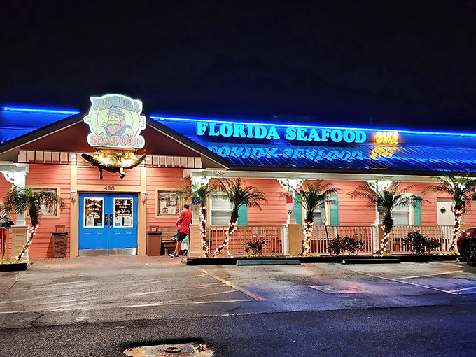 The coral-pink exterior glows like a neon-lit treasure chest at night, beckoning hungry seafood lovers with its maritime charm and promise of oceanic delights.