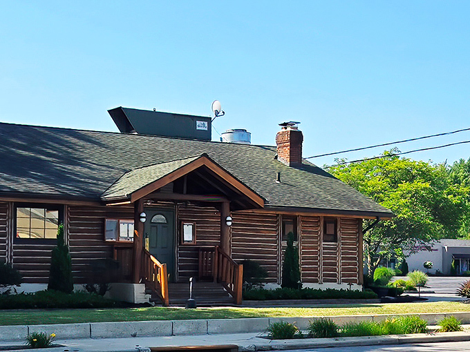 The rustic log cabin exterior of Cabin Club stands proudly on Detroit Road, like a luxurious woodland retreat that happens to serve exceptional steaks.