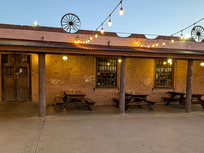 Desert sunset transforms this humble adobe exterior into a glowing beacon of culinary promise. String lights and wagon wheels telegraph what awaits: authentic Western charm.