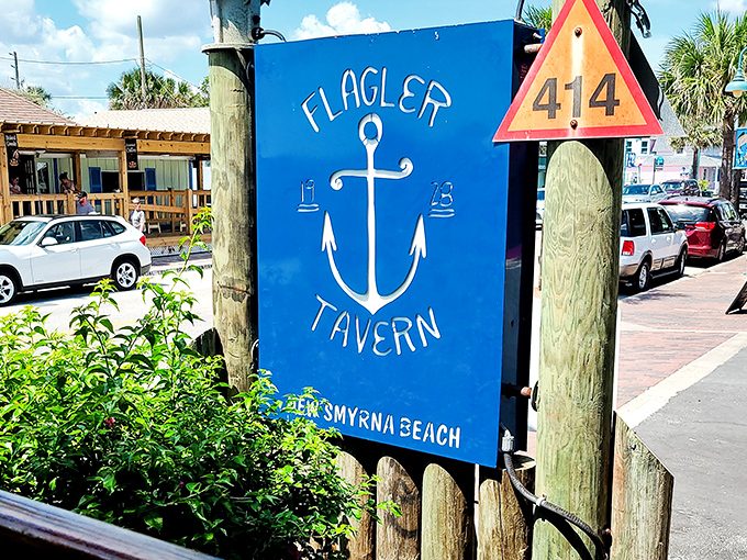 The iconic blue anchor sign welcomes seafood pilgrims to Flagler Tavern, where coastal charm begins before you even step inside.