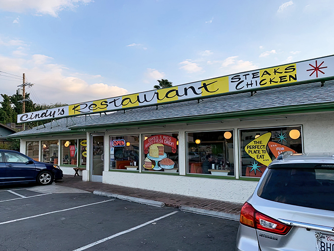 The iconic yellow sign beckons like a beacon of comfort food salvation. Cindy's Restaurant stands proudly against the California sky, promising steaks, chicken, and diner perfection.