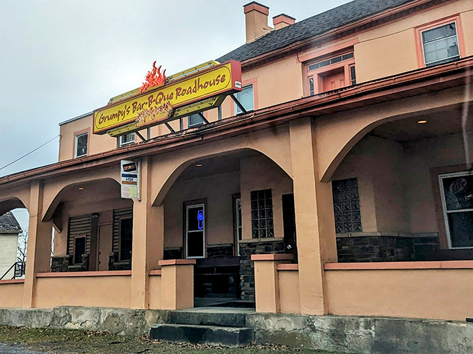 The peach-colored exterior of Grumpy's stands like a barbecue beacon, its flame-adorned sign promising smoky delights within. No fancy frills needed when the food does the talking.