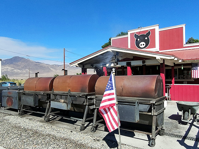 The iconic red exterior of Copper Top BBQ with its lineup of serious smokers standing like sentinels, ready to transform ordinary meat into extraordinary memories.