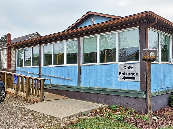 That "Caf&eacute; Entrance" sign might as well say "Portal to Comfort Food Heaven." The blue siding and sunlit windows promise zero pretension and maximum satisfaction.