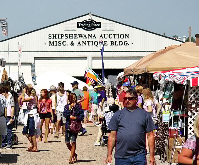 The bustling heart of Midwest treasure hunting! Shoppers navigate the maze of vendors outside the iconic Shipshewana Auction building on a perfect summer day.