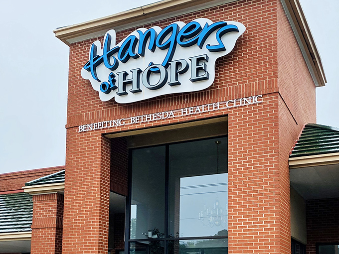 The bright blue Hangers of Hope sign against brick promises more than just retail therapy&mdash;it's shopping with a side of soul.
