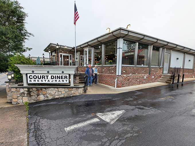 An American flag waves above Court Diner like a patriotic beacon guiding hungry travelers to this temple of breakfast perfection.