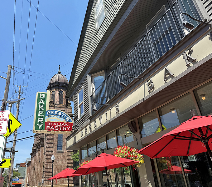 The iconic vertical "BAKERY" sign has guided hungry pilgrims to this Little Italy landmark for generations. Red umbrellas promise sweet shelter for pastry enthusiasts.