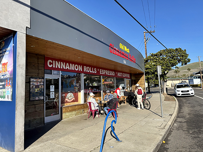 Morning pilgrims gather outside, drawn by the siren call of cinnamon and sugar. The blue bike rack seems to say, "Park here, burn calories later."