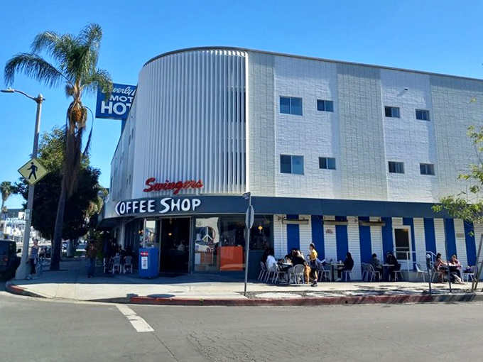 The iconic curved exterior of Swingers Diner stands like a mid-century time capsule on Beverly Boulevard, palm trees swaying in approval.