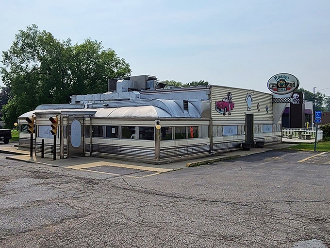 The classic aluminum exterior of Nancy's Main Street Diner gleams in the sunlight, complete with vintage car artwork that promises a journey back to simpler times.