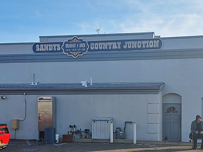 The white-washed exterior of Sandy's Country Junction welcomes hungry travelers with rustic charm and a shaded patio that practically whispers, "Come sit a spell."
