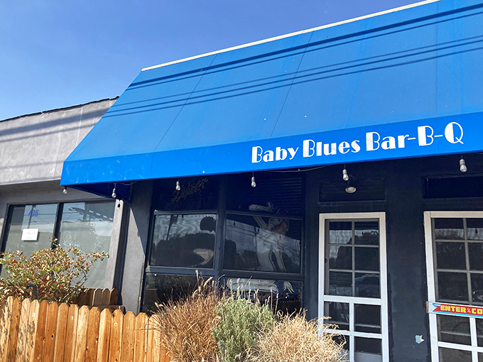 That iconic blue awning and wooden fence might not scream "barbecue mecca," but your nose will know the truth before you even reach the door.