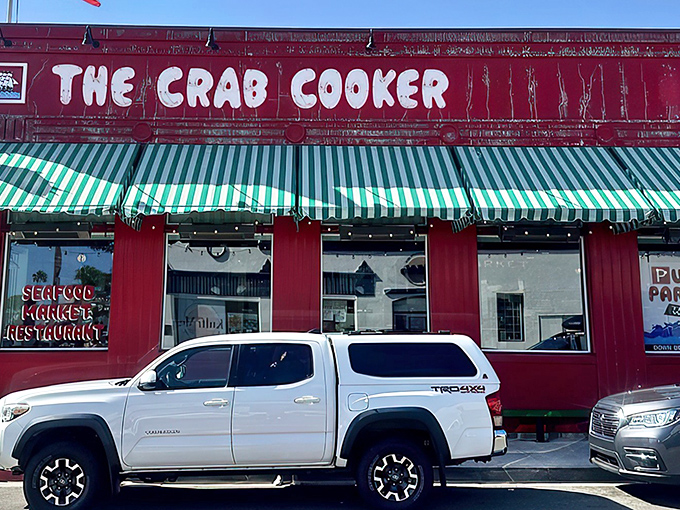 The crimson beacon of Newport Beach beckons seafood lovers like a maritime lighthouse. The Crab Cooker's iconic red exterior and green-striped awnings promise no-nonsense deliciousness inside.