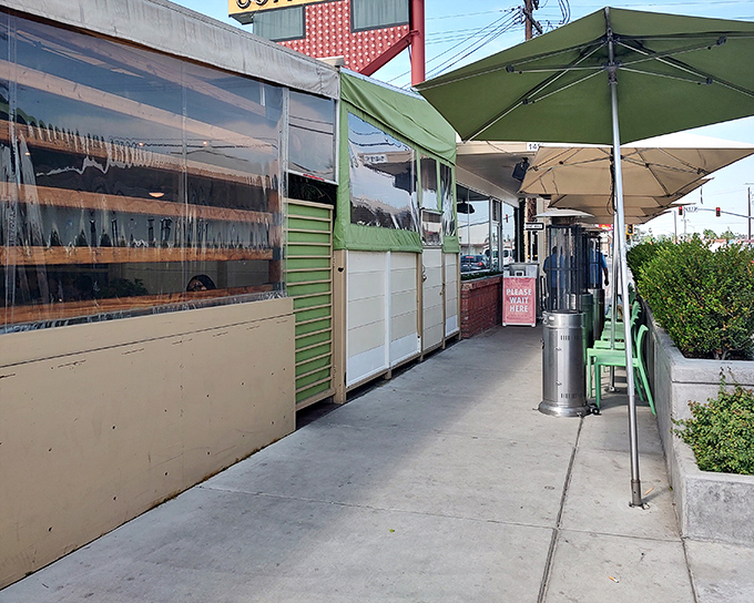 The unassuming exterior of 24th Street Cafe, where green umbrellas promise shade and the promise of comfort food beckons from within.