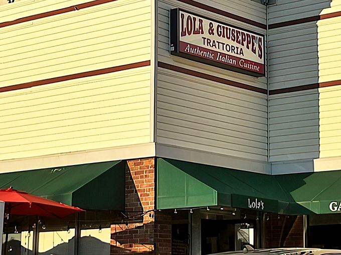 The unassuming exterior of Lola & Giuseppe's Trattoria, where green awnings and a simple sign hide culinary treasures that would make any Italian grandmother proud.