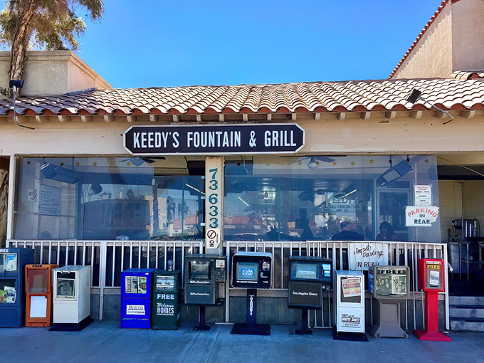 The classic facade of Keedy's Fountain & Grill stands proudly in Palm Desert, newspaper boxes standing guard like sentinels of a simpler time.