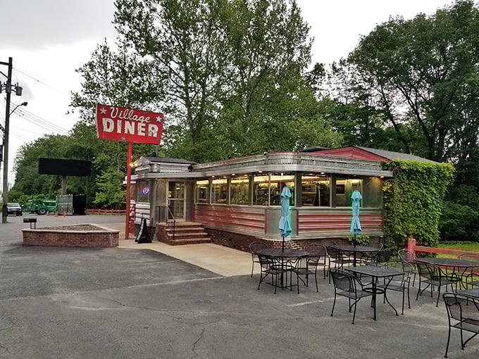 The classic stainless steel exterior of Village Diner gleams like a beacon of hope for hungry travelers. Those teal umbrellas promise a perfect spot for summer dining.