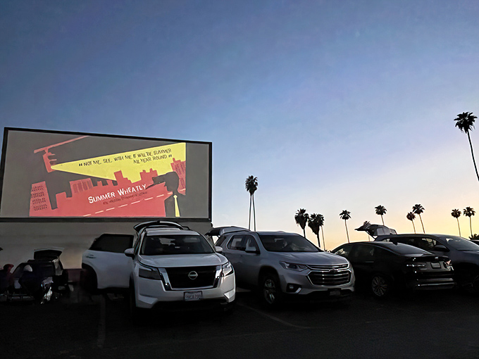 Twilight magic at the Van Buren Drive-In, where palm trees silhouette against the fading sky as moviegoers settle in for showtime.