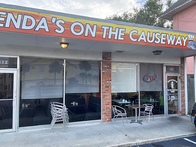 The vibrant orange storefront of Brenda's On the Causeway stands like a sunrise beacon for hungry travelers along Dunedin's waterfront.