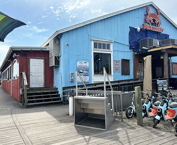 The bright blue exterior of Pinchers stands out like a cheerful maritime flag, beckoning seafood lovers with its weathered wooden charm and promise of fresh catches.