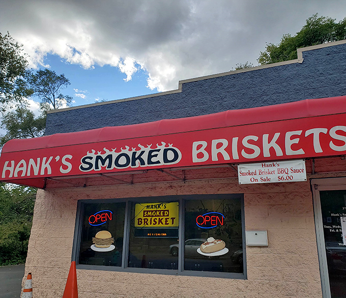 The iconic red awning of Hank's Smoked Briskets stands out like a beacon for BBQ pilgrims. Those neon "OPEN" signs might as well say "HEAVEN."