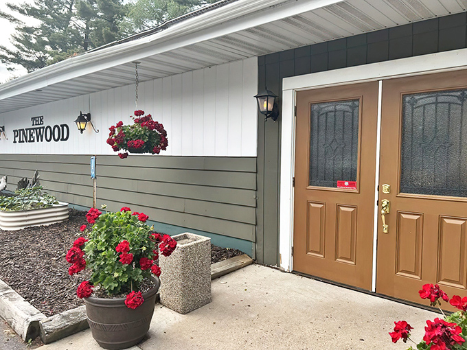 The welcoming entrance to Pinewood Supper Club, where hanging flower baskets and warm lighting promise the authentic Wisconsin supper club experience awaits inside.
