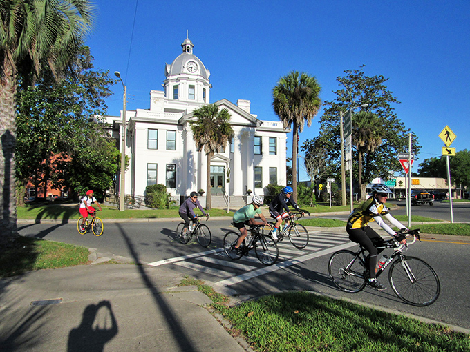 Downtown Monticello blends timeless charm with modern motion, where cyclists glide past stately buildings and palm-lined streets, capturing the essence of peaceful, stress-free small-town living.
