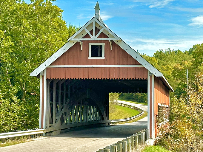 The Netcher Road Covered Bridge stands like a crimson sentinel against Ohio's blue skies, its classic design practically begging for a postcard moment.
