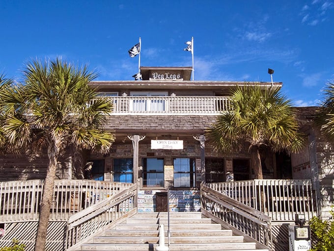 The weathered wooden exterior of Peg Leg Pete's stands like a salty sea captain, palm trees swaying in greeting as you approach this Pensacola Beach treasure.