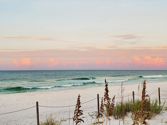 Nature's own watercolor masterpiece. The sunset paints cotton candy clouds over emerald waters while sea oats stand guard like nature's velvet rope. 