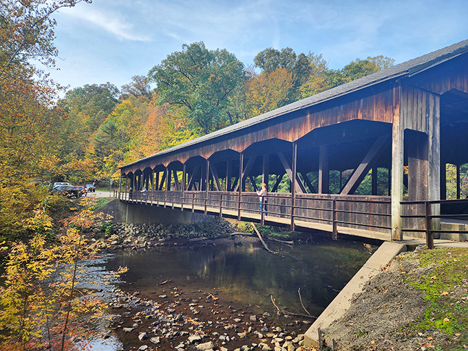 Nature's perfect postcard: The covered bridge at Mohican State Park frames autumn's fiery display while spanning the gentle Clear Fork River below.