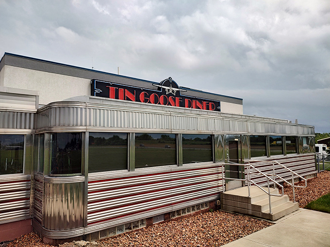 The gleaming stainless steel exterior of The Tin Goose Diner shines like a beacon of nostalgia, promising comfort food and a side of aviation history.