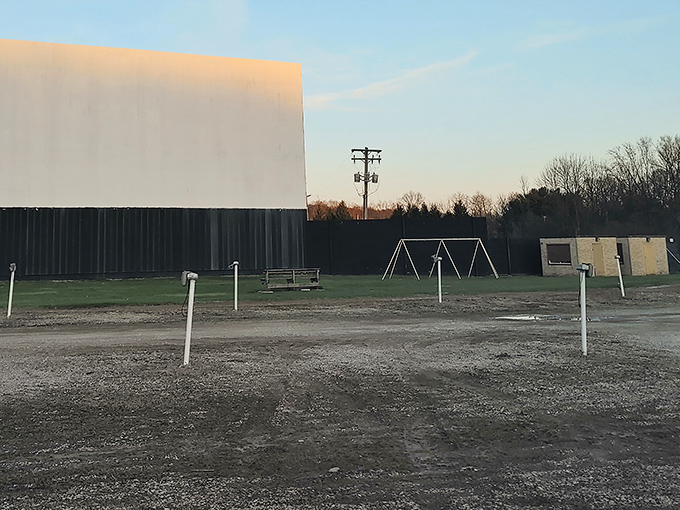 The massive white screen at Magic City Drive-In stands ready for showtime, a blank canvas awaiting cinematic magic as dusk approaches.