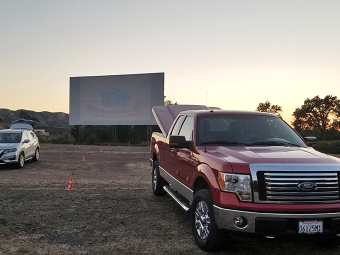 A classic red pickup claims prime viewing territory as twilight settles over Clear Lake's hills. Some traditions just know how to age gracefully.