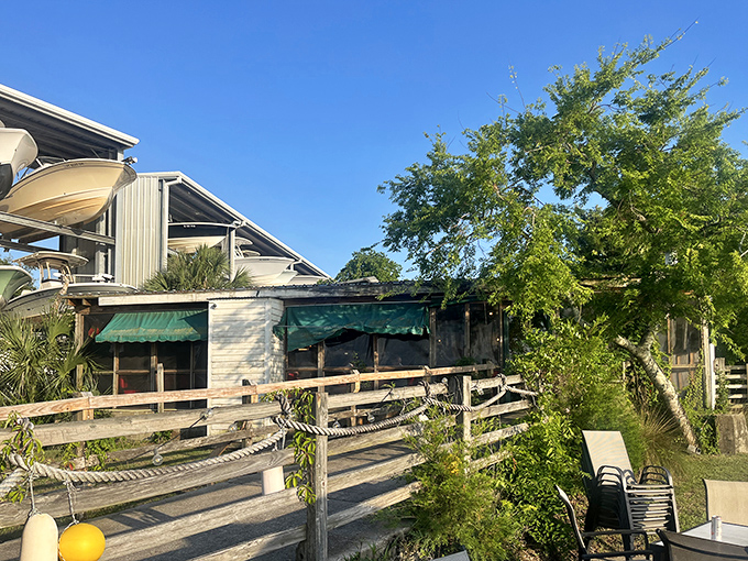 Rustic charm meets waterfront dining at The Wreck's exterior, where weathered wood and green awnings hint at the no-frills seafood feast waiting inside.