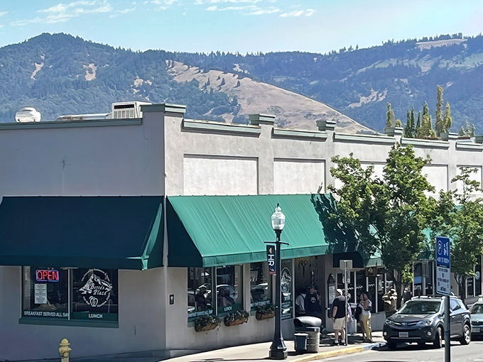 Downtown Hood River's culinary cornerstone stands proudly with its green awning, while the Cascade Mountains play backdrop like nature's own dining room mural.