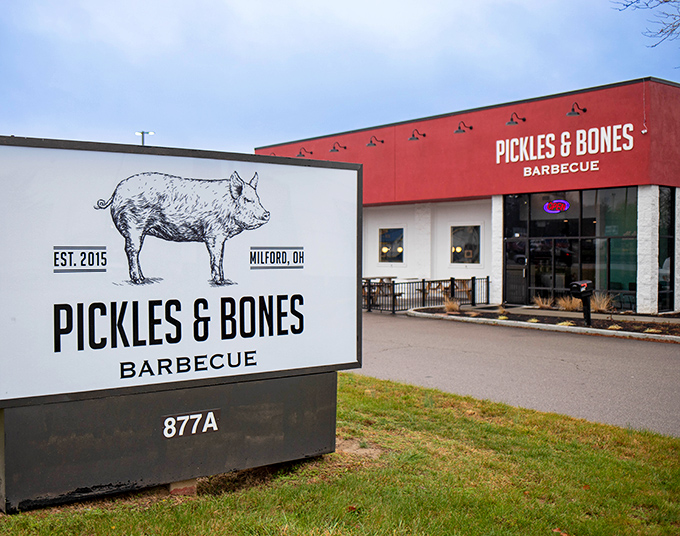 The iconic red exterior of Pickles & Bones stands like a barbecue beacon in Milford, with its hand-drawn pig logo promising smoky delights within.