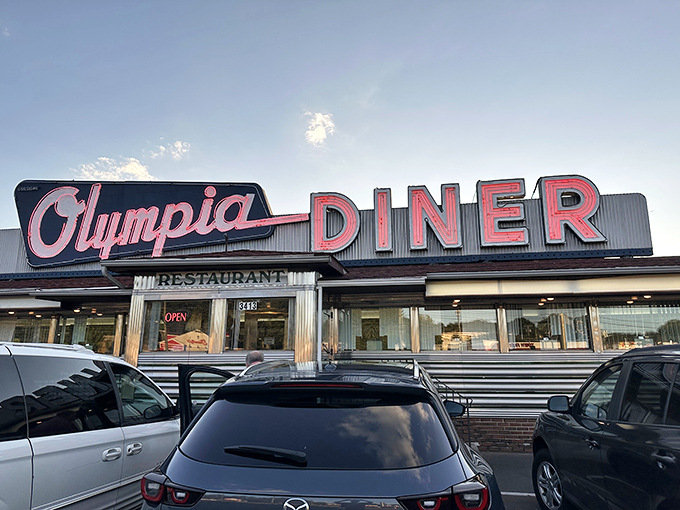 That iconic neon sign beckons hungry travelers like a lighthouse for the breakfast-starved. Even in twilight, Olympia Diner promises salvation from fast-food mediocrity.