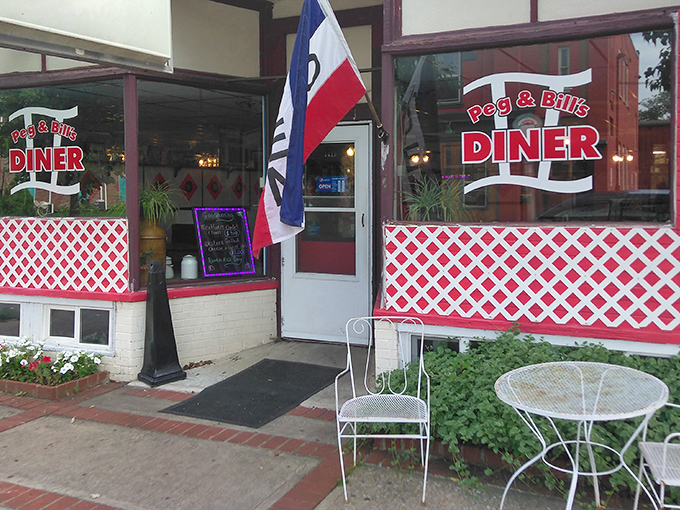 The welcoming entrance to Peg & Bill's Diner, where classic red lattice and an "OPEN" flag promise authentic Pennsylvania comfort food inside.