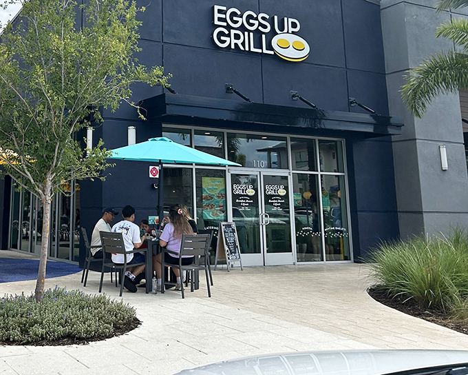 The sleek black exterior of Eggs Up Grill belies the breakfast wonderland within. That cheerful yellow logo is basically a bat signal for pancake enthusiasts.