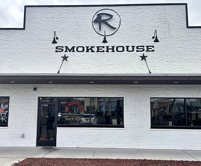 The white brick exterior of 4 Rivers Smokehouse stands like a beacon of barbecue hope, its iconic "4R" logo promising smoky delights within.