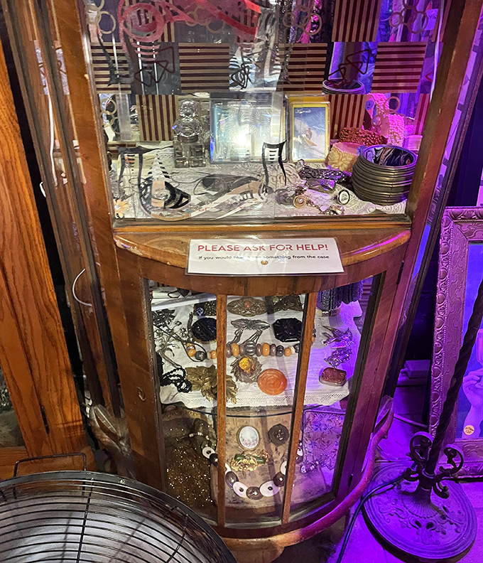 Purple lighting transforms ordinary jewelry displays into treasure chests with a sign politely requesting help&mdash;because some treasures require guidance.