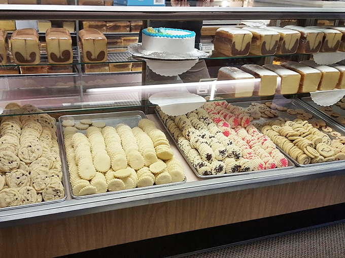 The display case offers a museum-worthy collection where butter, sugar, and flour achieve their highest artistic expression.